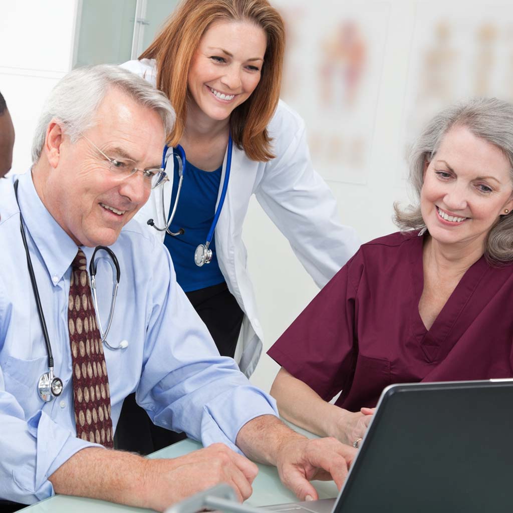 Happy Medical Team Looking at Laptop in Doctor's Office. Happy Medical Team Looking at Laptop in Doctor's Office.