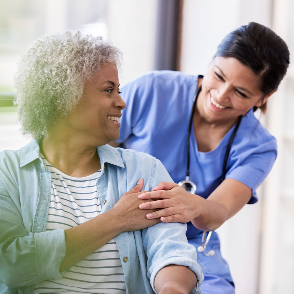 An elderly woman in a wheelchair is helped by a friendly nurse An elderly woman in a wheelchair is helped by a friendly nurse